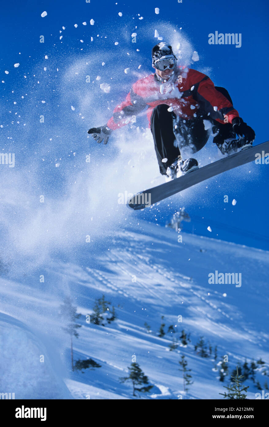 Snowboarder mid-air above ski Slope, snow powder trailing behind Stock ...