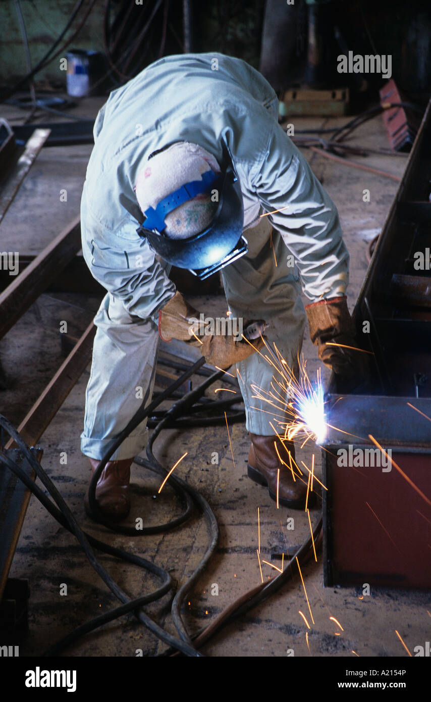 Welder bending down, welding at Work Stock Photo - Alamy