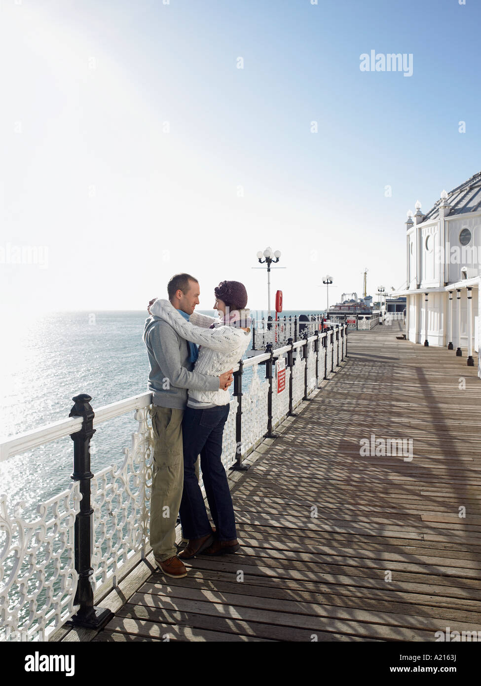 Couple embracing, standing on pier, side view, full length Stock Photo ...