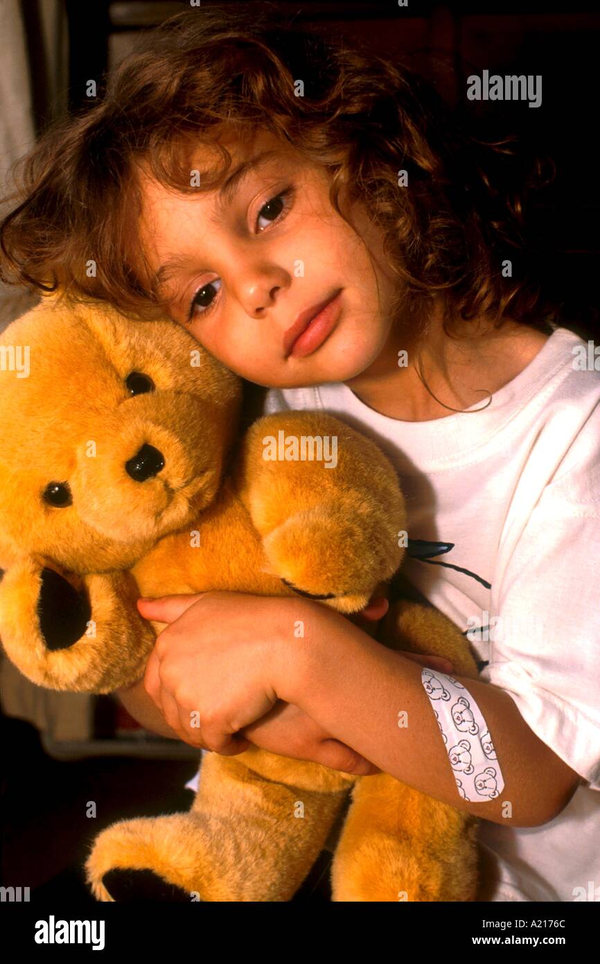 Young girl cuddling teddy bear with plaster on her arm J Legate Stock ...