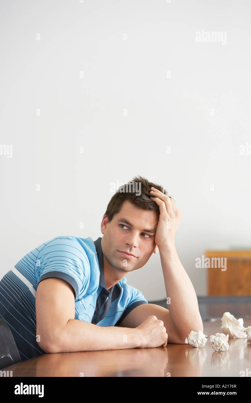 Frustrated Man sitting at conference table With Crumpled Paper looking ...
