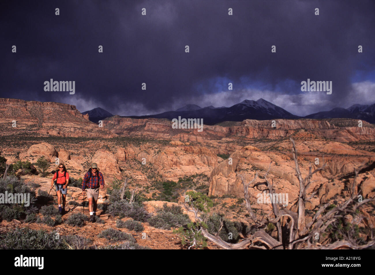 A couple hiking under storm clouds near Moab Utah Stock Photo - Alamy