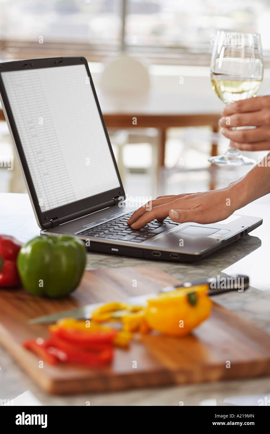 Man using lap top and chopping peppers in kitchen, close up of hands ...