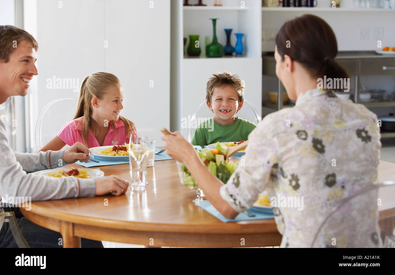 Family eating dinner at round table, in kitchen Stock Photo - Alamy