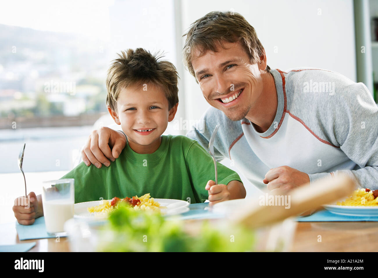 Father and son sitting at table eating pasta Stock Photo - Alamy