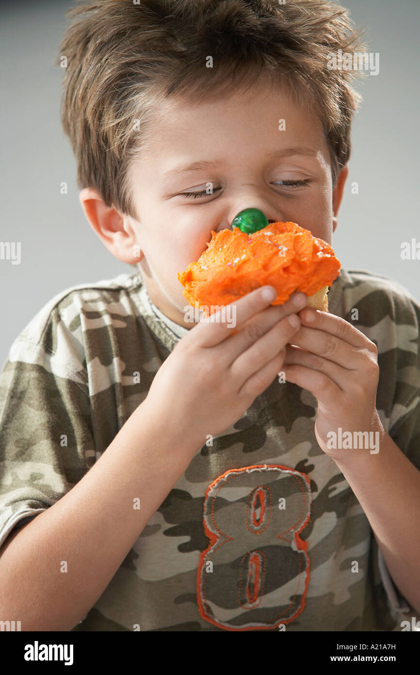 Young boy eating cupcake, half length Stock Photo - Alamy