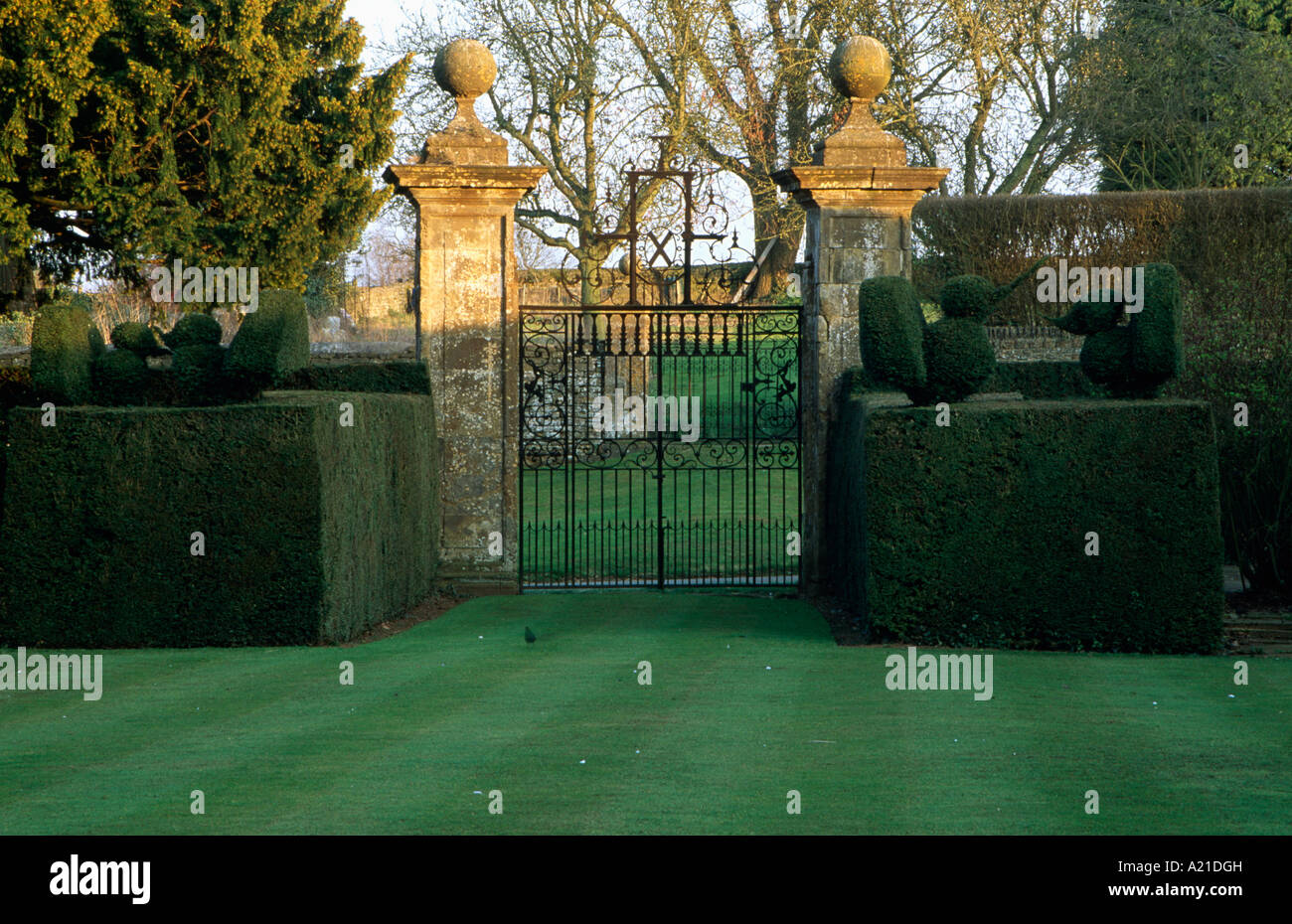 Lawn in front of large garden gates with stone pillars and clipped ...