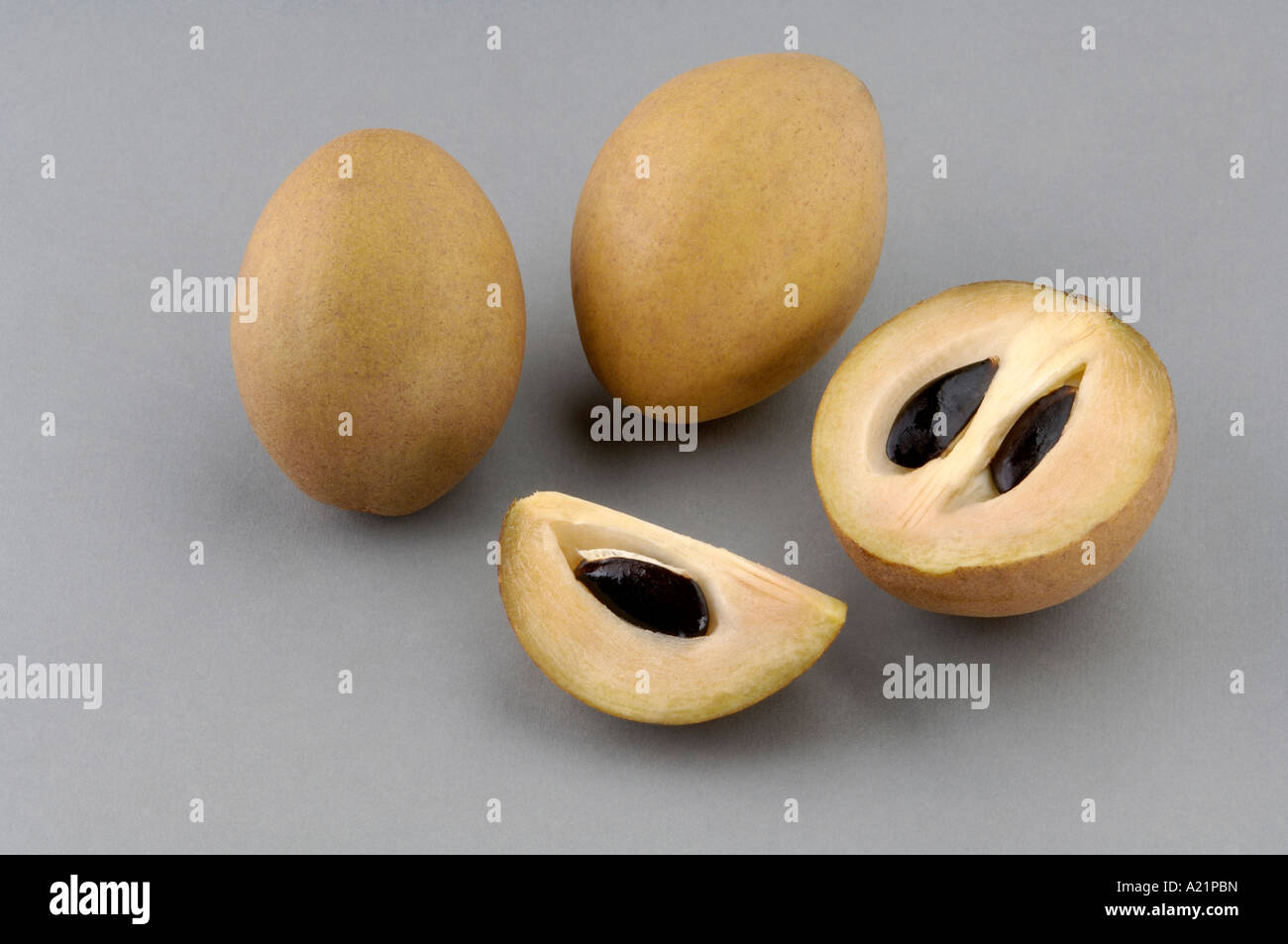 Three Chickoo two full one half cut food fruit on grey background Stock ...