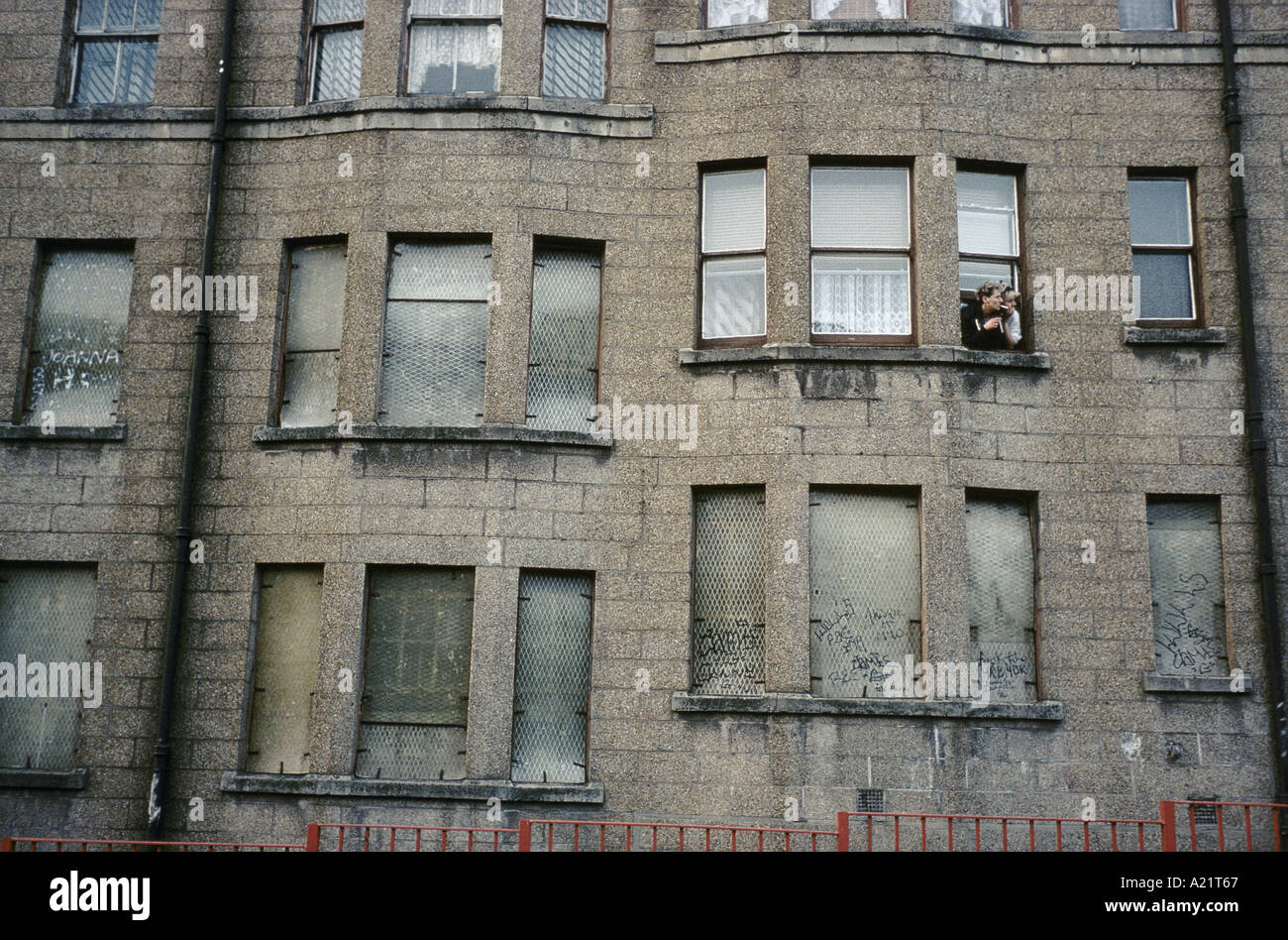 A couple leaning out of the window smoking, Possil Park Estate, Glasgow ...