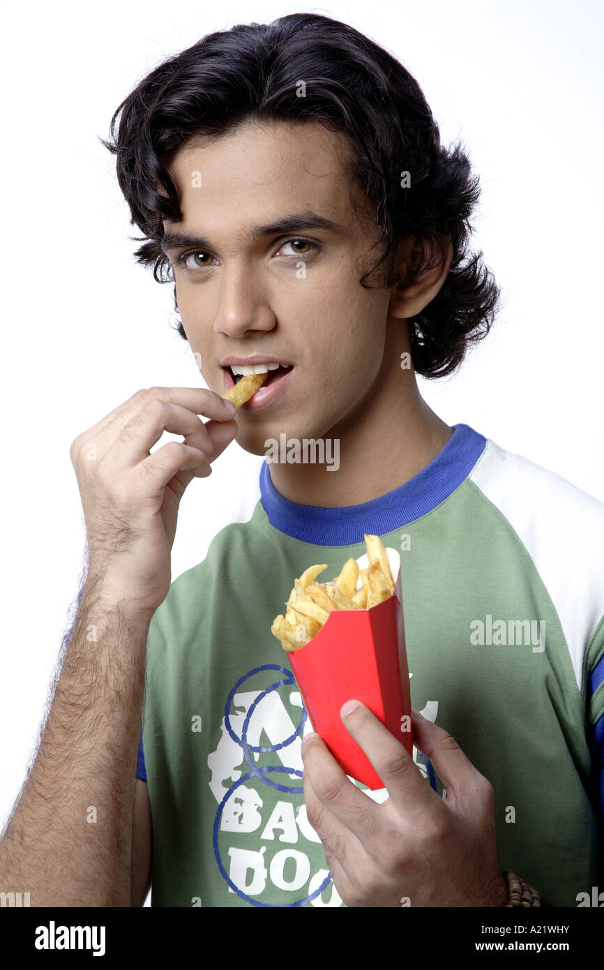Teenage boy standing holding packet of potato finger chips French fries ...