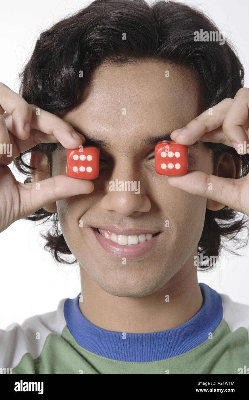 ANG200483 Teenage boy holding two red colored dices in front of his ...