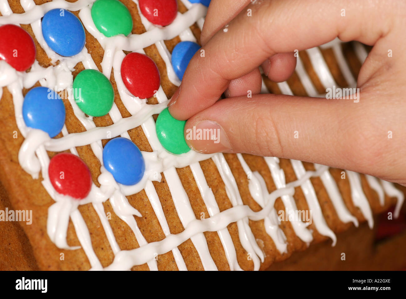 Decorating a gingerbread house roof with candies Stock Photo - Alamy