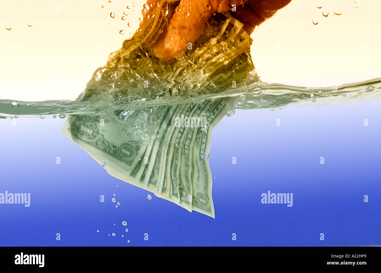 hand holding dollar bills US dipping into water making splash and ...