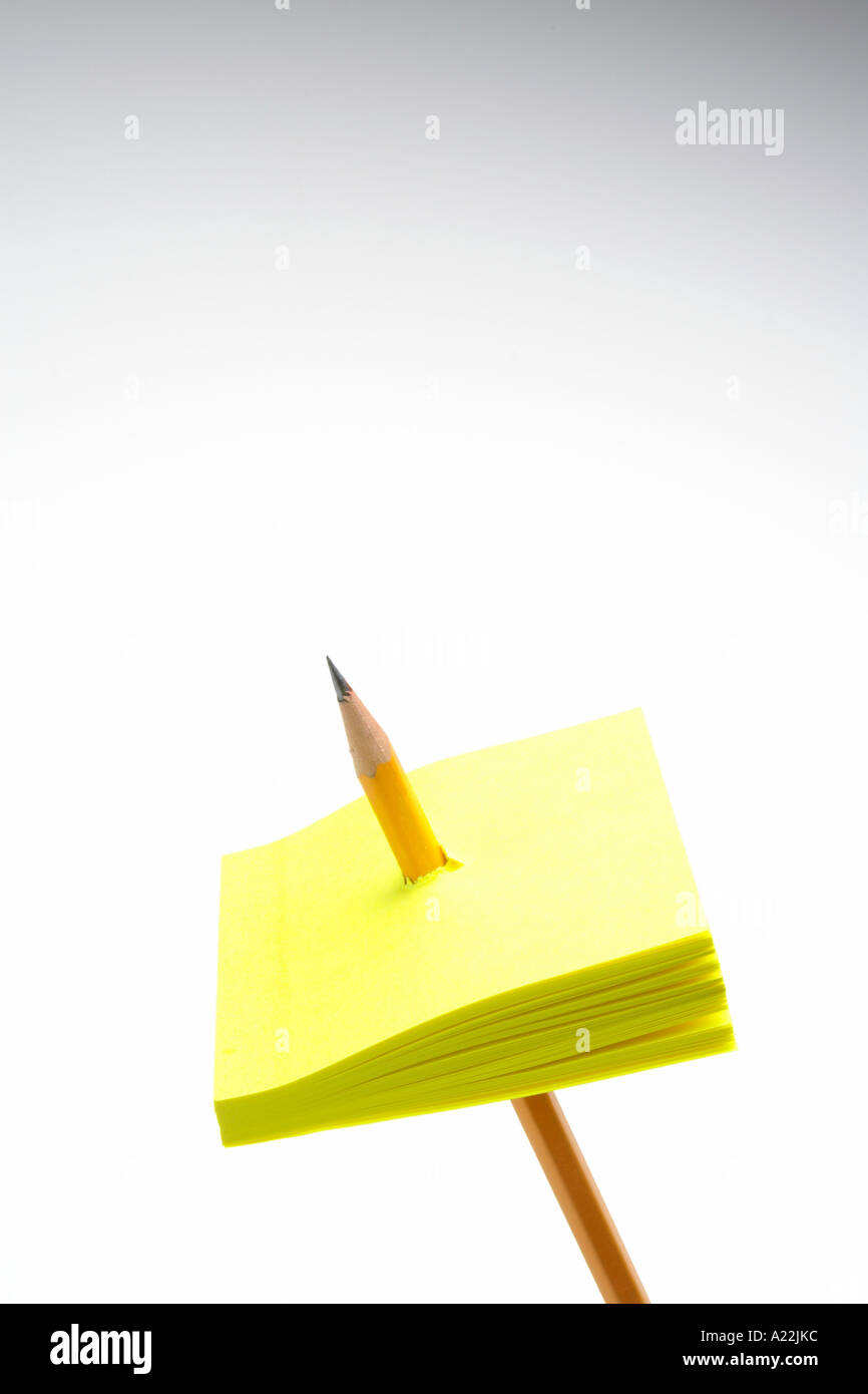 pencil punched thru yellow sticky note pad Stock Photo - Alamy