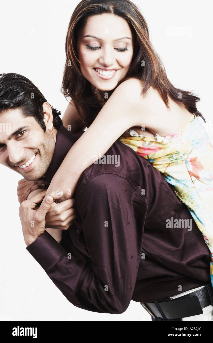 Portrait of a young woman riding piggyback on a young man Stock Photo ...
