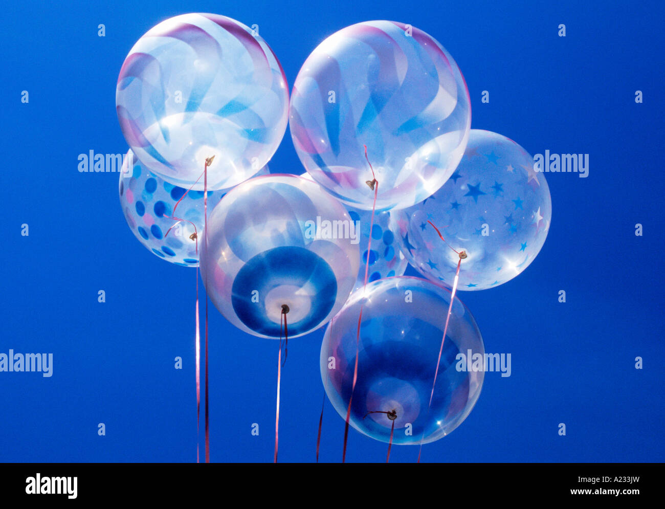 Several tethered toy balloons against a blue sky Stock Photo - Alamy