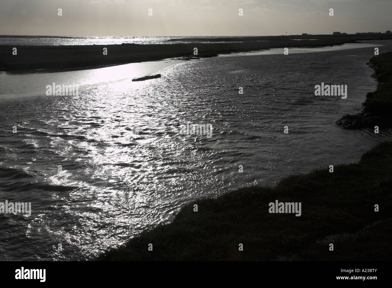 Sun shining on water of River Ore and Orford Ness spit Suffolk, England ...