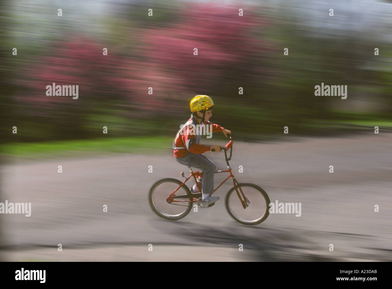 Young boy riding bicycle wearing safety helmet zips by fast on a street ...
