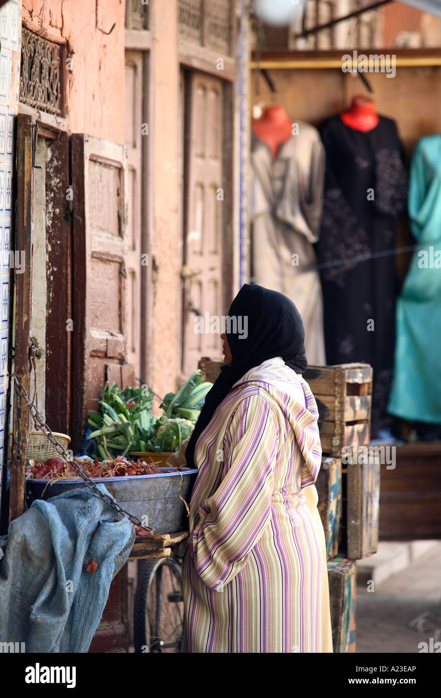 a moroccan woman in traditional clothing shops for vegetables in the ...