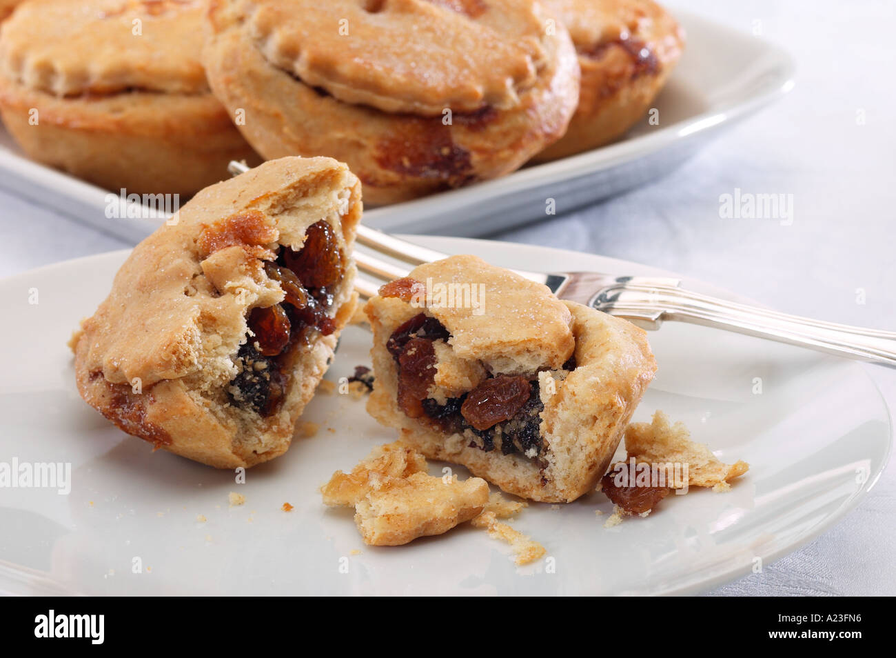 Single mince pie cut in half on white plate with fork, other behind ...