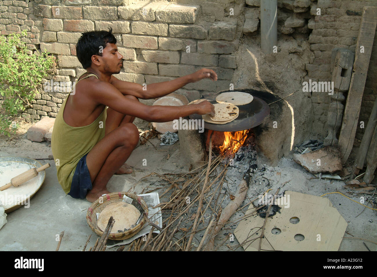 Typical Indian village man baking his fresh bread on natural wood fire ...