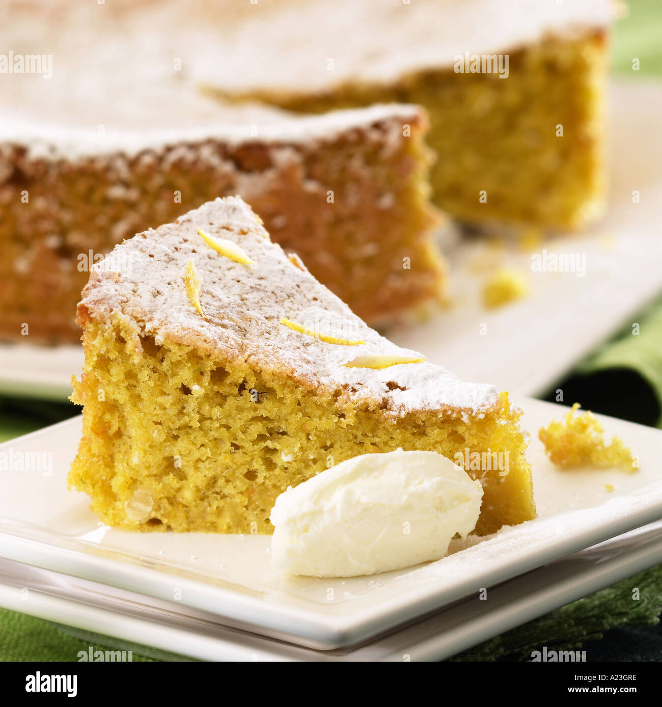 Olive oil cake slice with cream - whole cake in b/g Stock Photo - Alamy