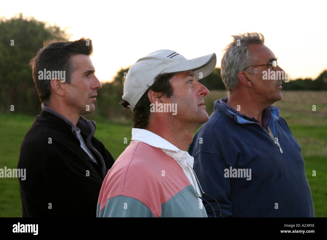 side view of three men looking into distance at something outside the ...