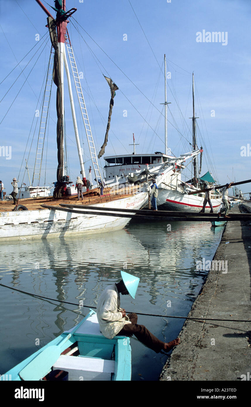 Fisherman resting on the side of his boat at the quayside in front of ...