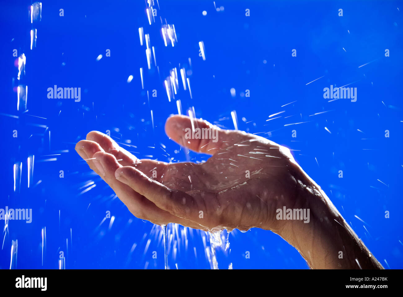 Hands splashed with running water against blue background Stock Photo ...