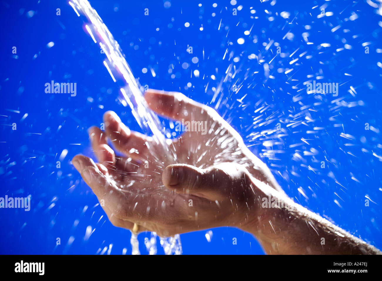 Hands splashed with running water against blue background Stock Photo ...