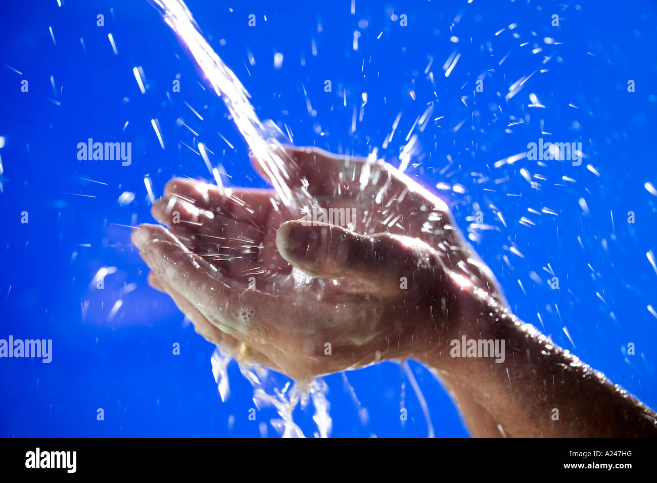 Hands splashed with running water against blue background Stock Photo ...