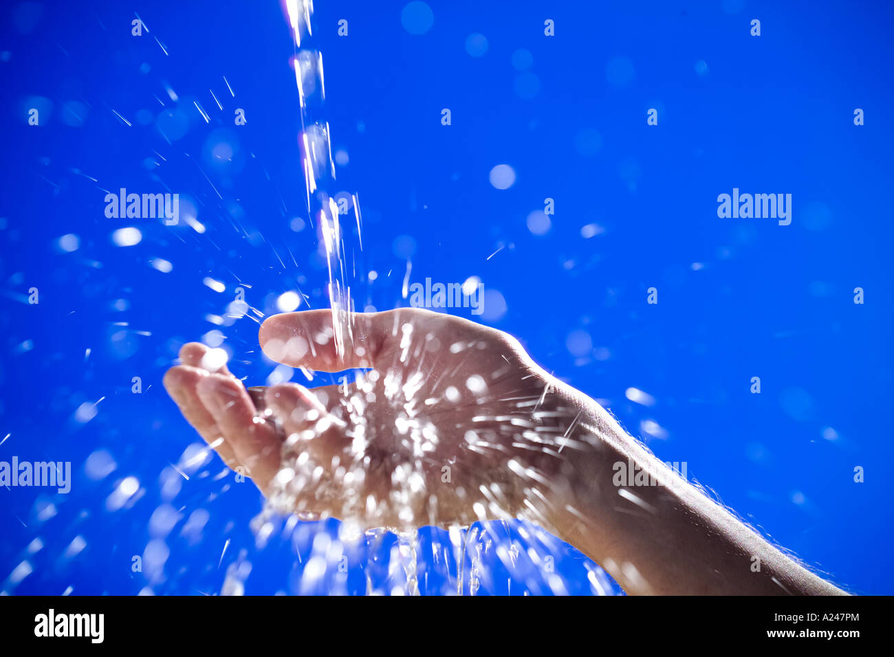 Hands splashed with running water against blue background Stock Photo ...