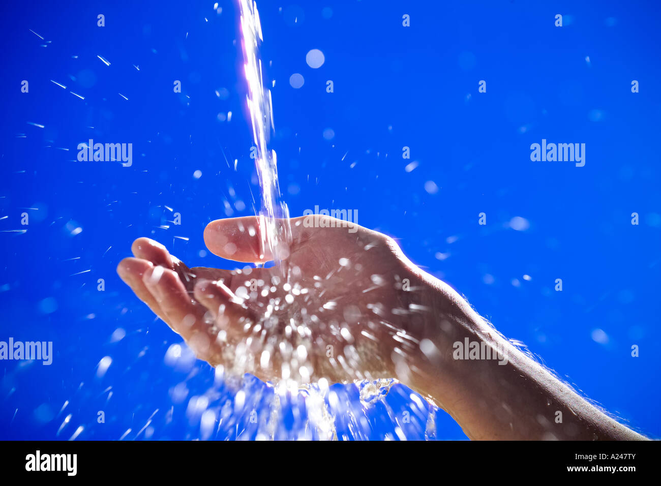Hands splashed with running water against blue background Stock Photo ...