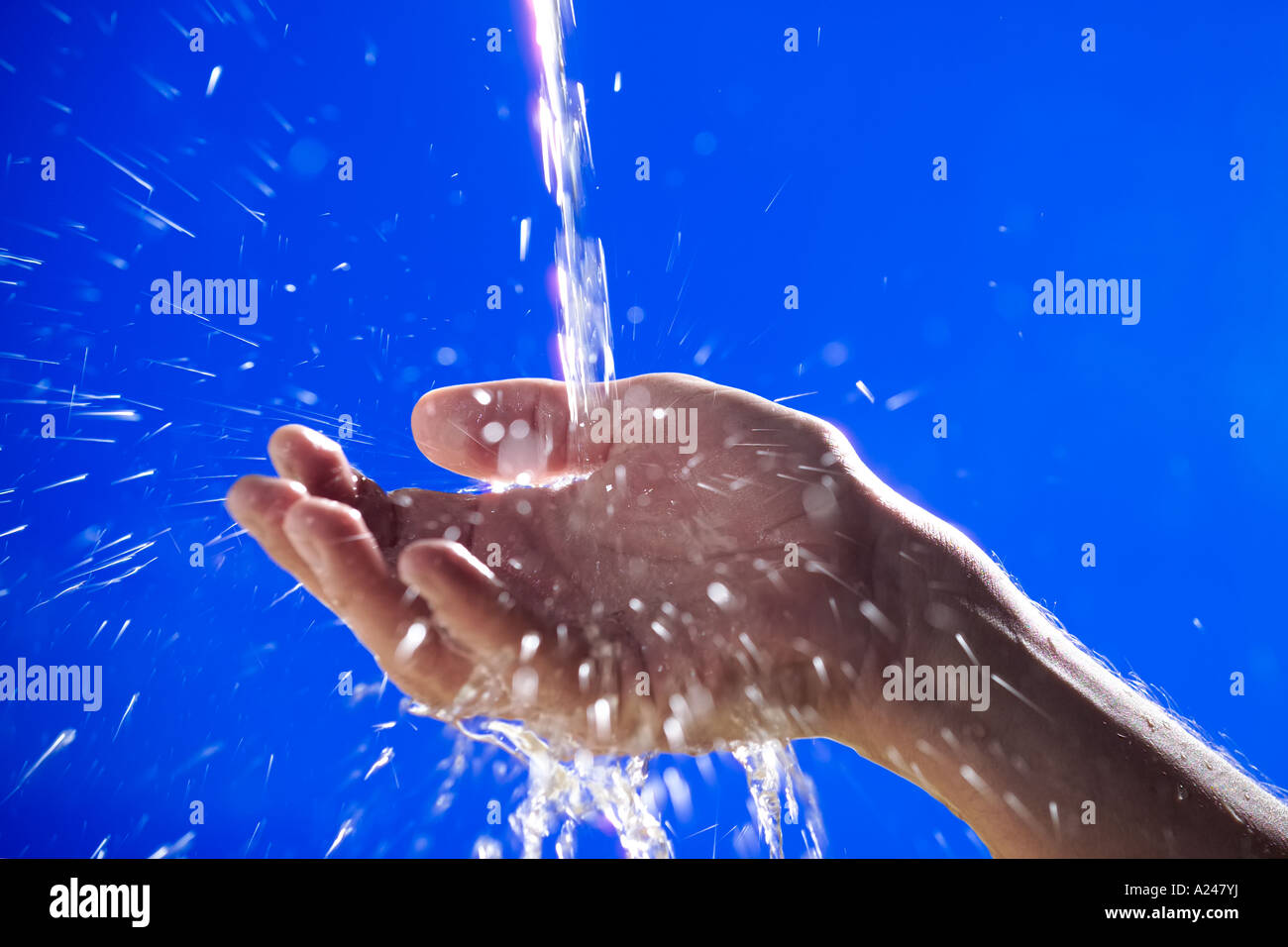 Hands splashed with running water against blue background Stock Photo ...