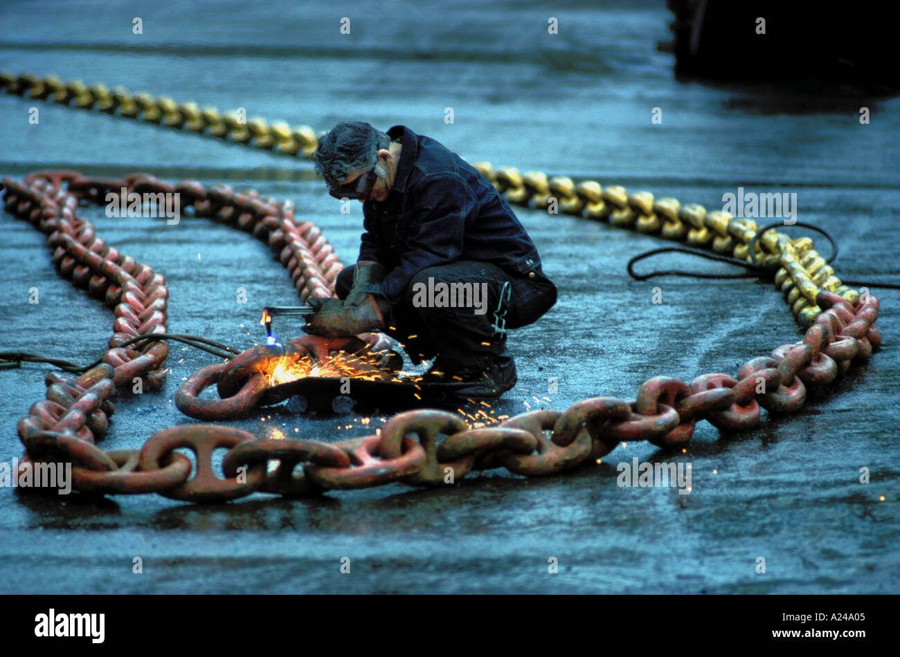 Welder working on an anchor chain in a Seattle Washington shipyard ...
