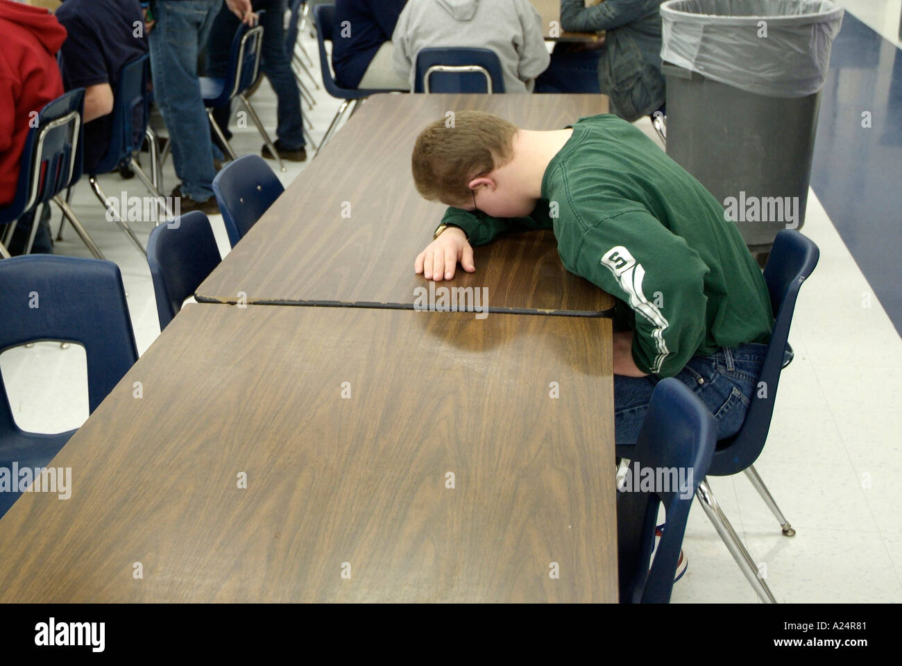Sick or ill high school student lays head on table in the cafeteria ...