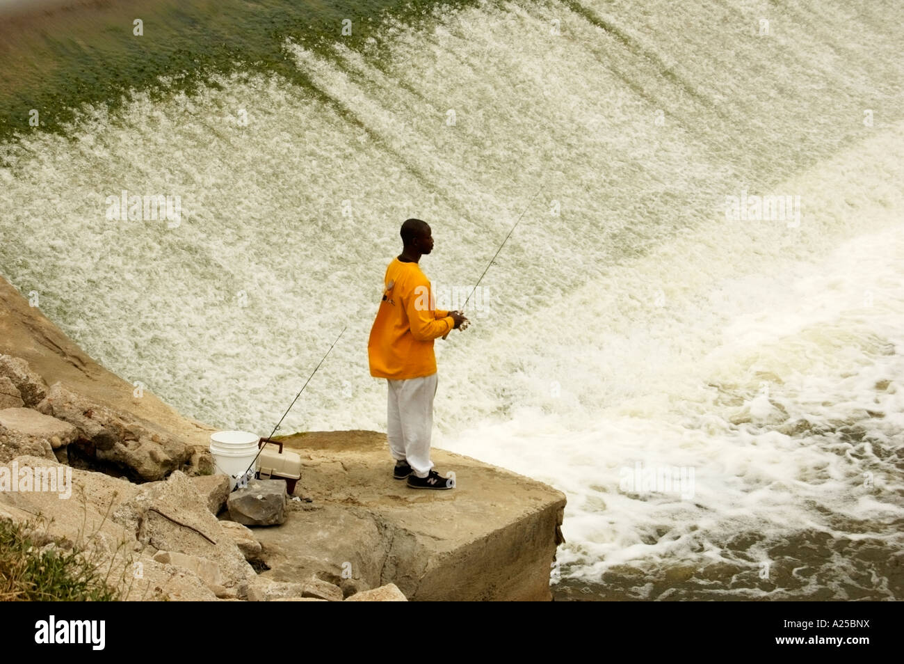 Young guy fishing below the dam Stock Photo - Alamy