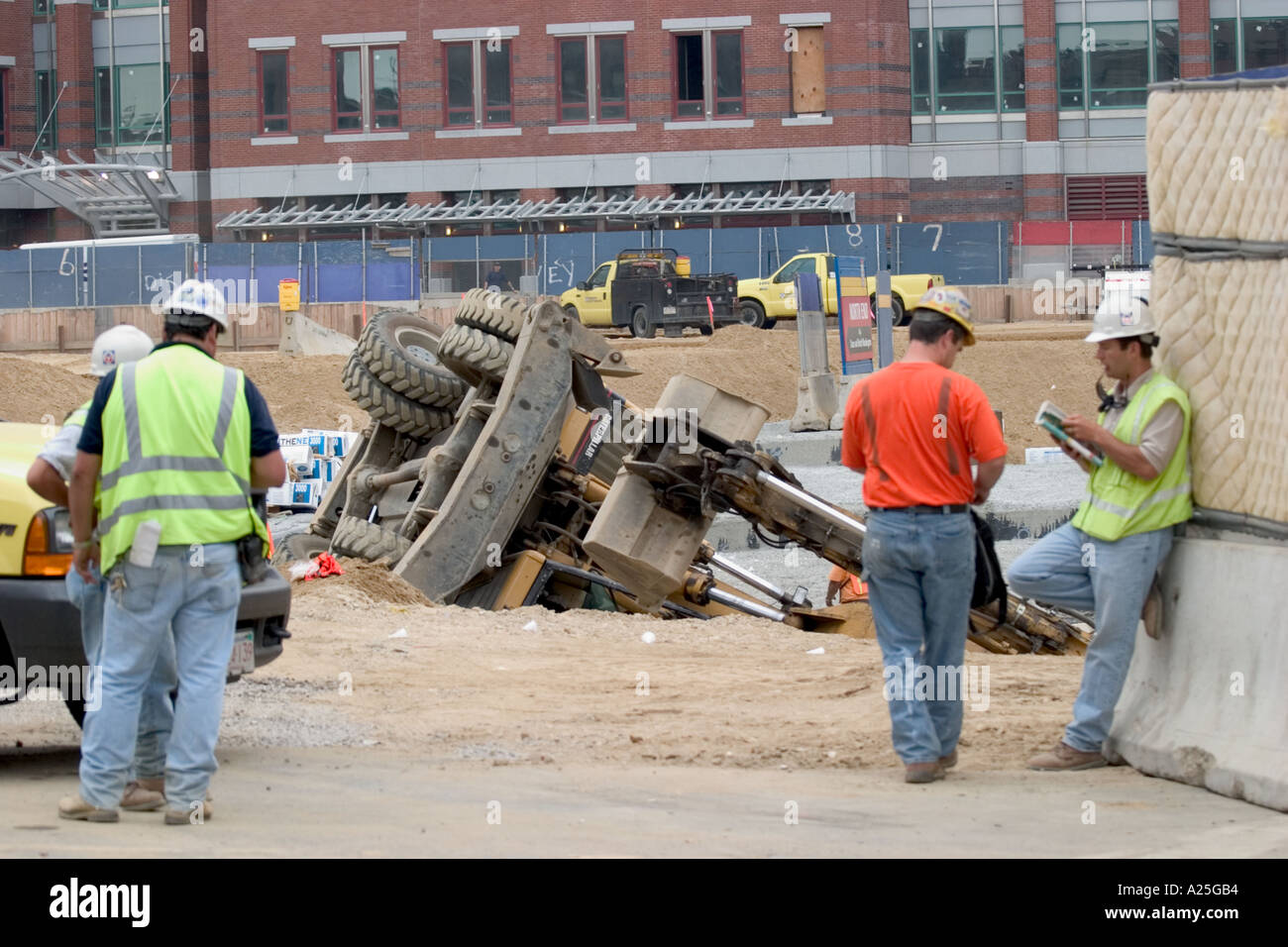 Workers looking at an overturned truck at a city construction site ...