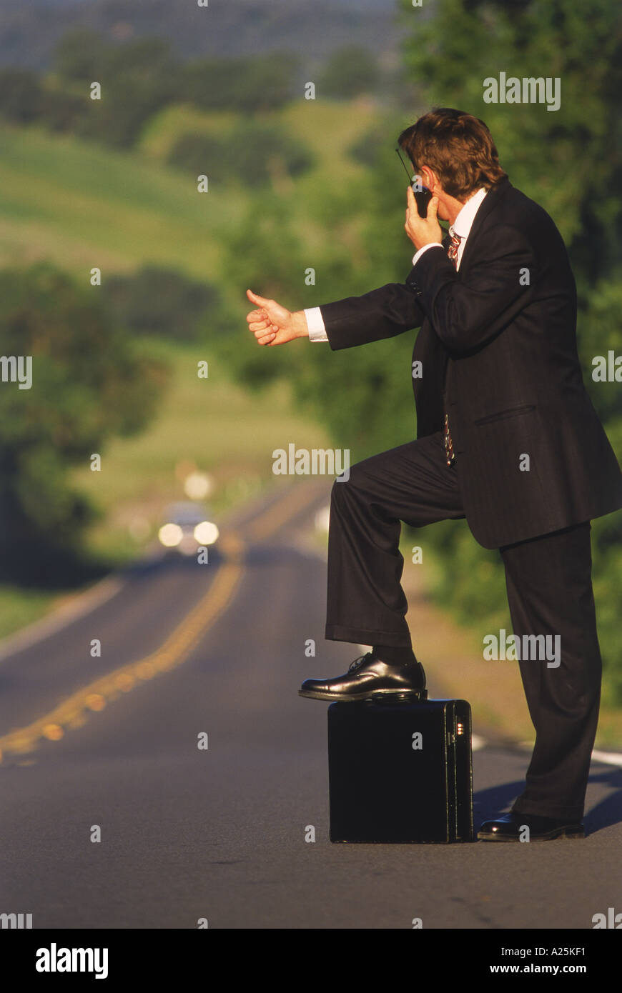 Businessman alone on highway trying to hitch a ride Stock Photo - Alamy