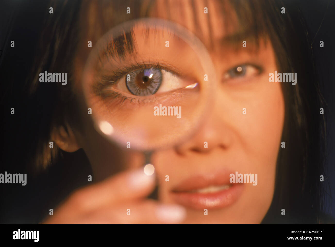 Asian woman looking through magnifying glass Stock Photo - Alamy