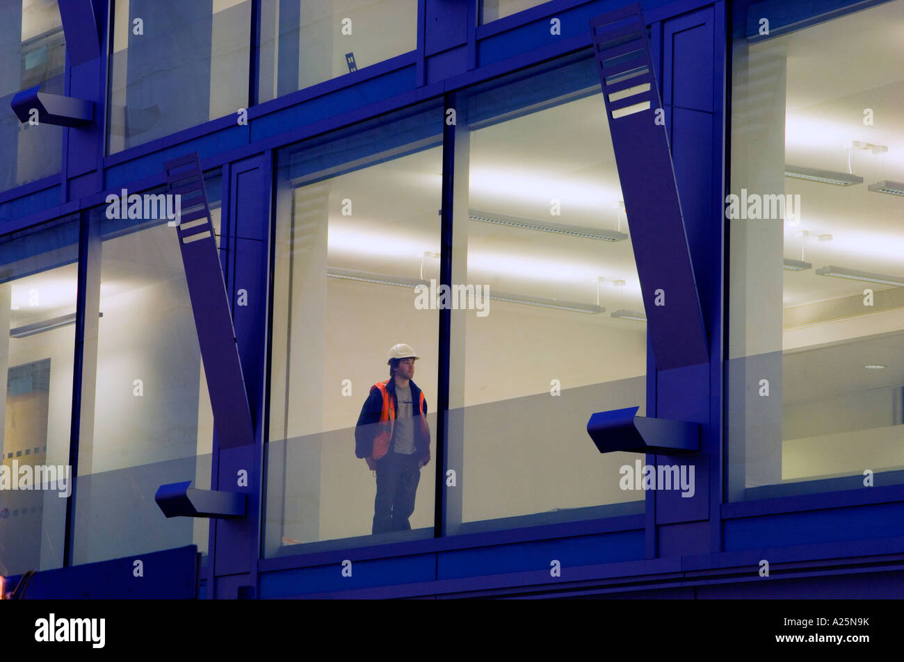 single male construction worker surveyor looking out of window of new ...