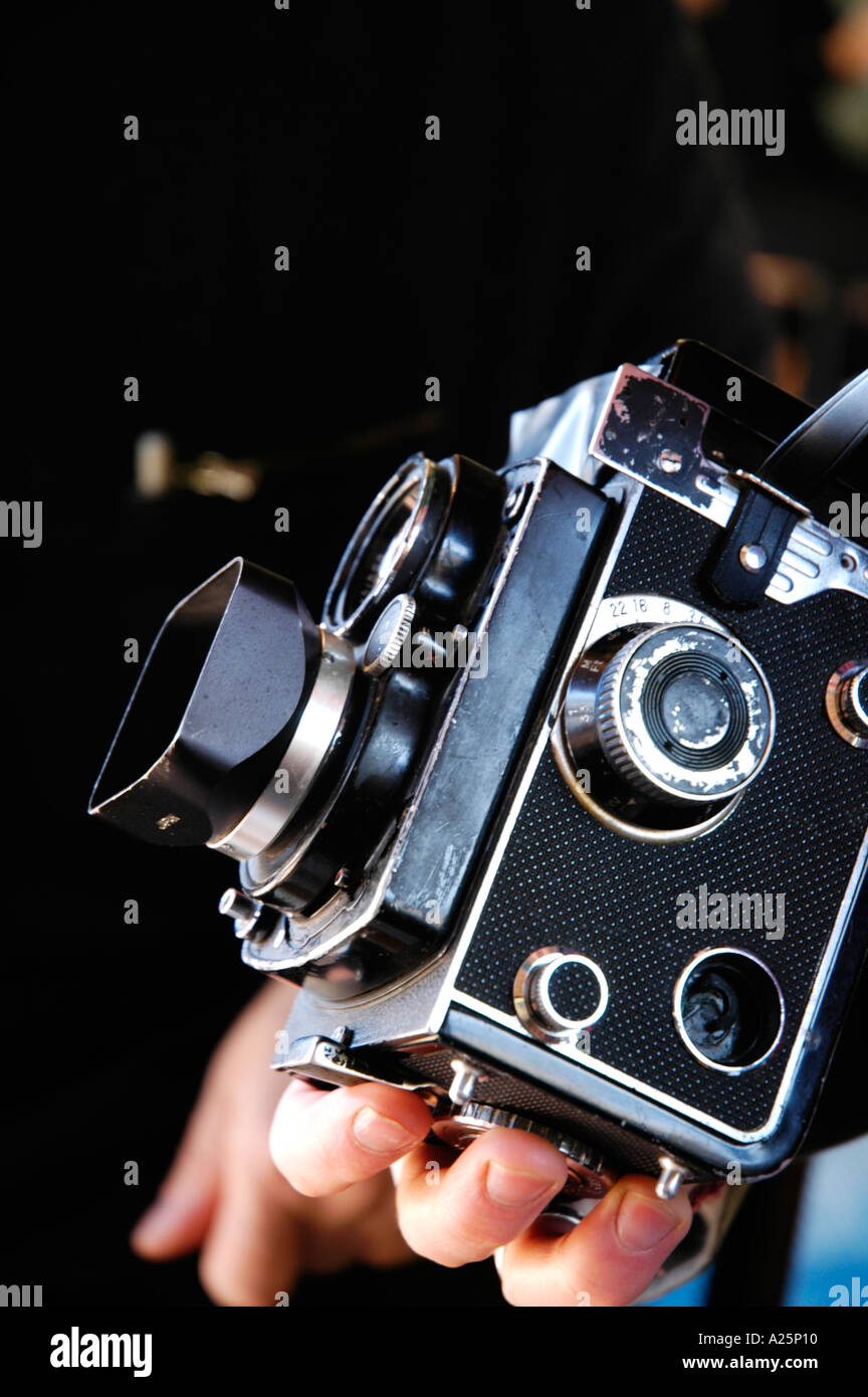 Old Yashica twin lens reflex camera being hand held against a black ...