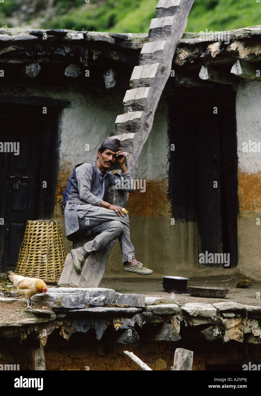 Traditional HIMALAYAN HOUSE with man sitting on log ladder below ...