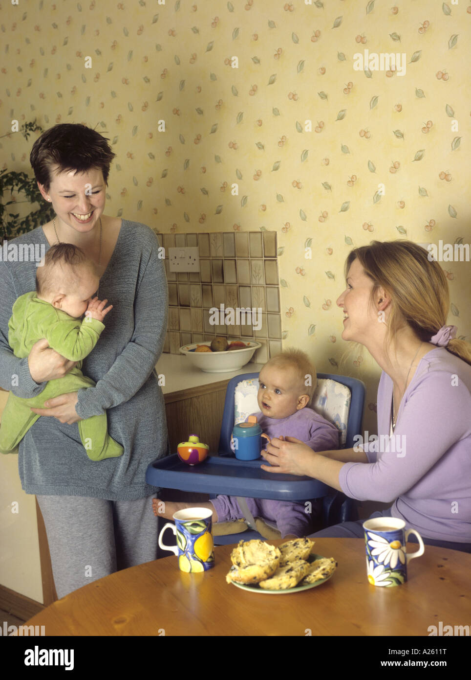 Women with their babies chatting and laughing together in a kitchen ...