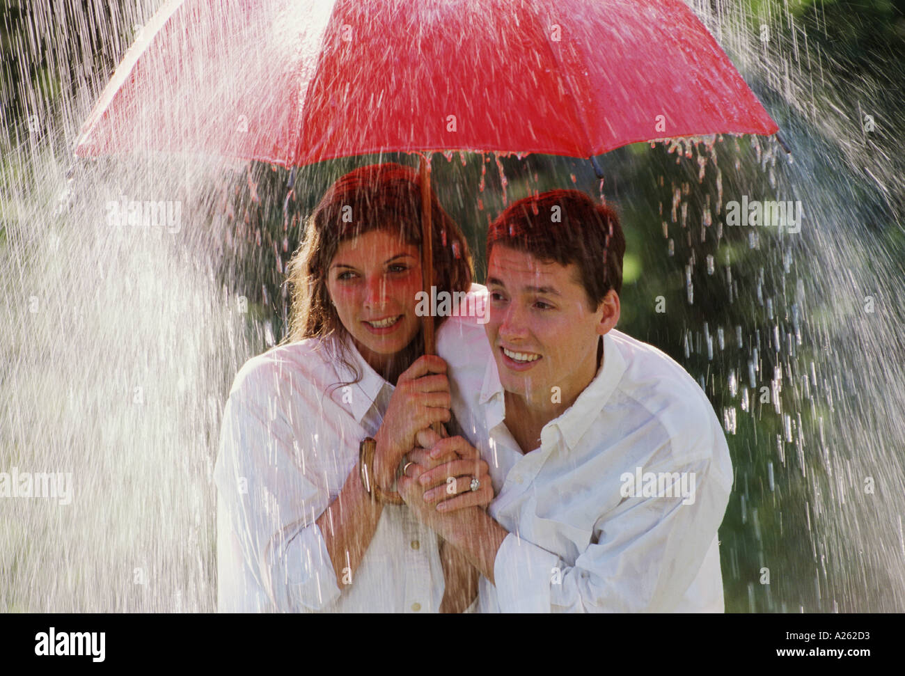 COUPLE SHELTERING UNDER UMBRELLA Stock Photo - Alamy