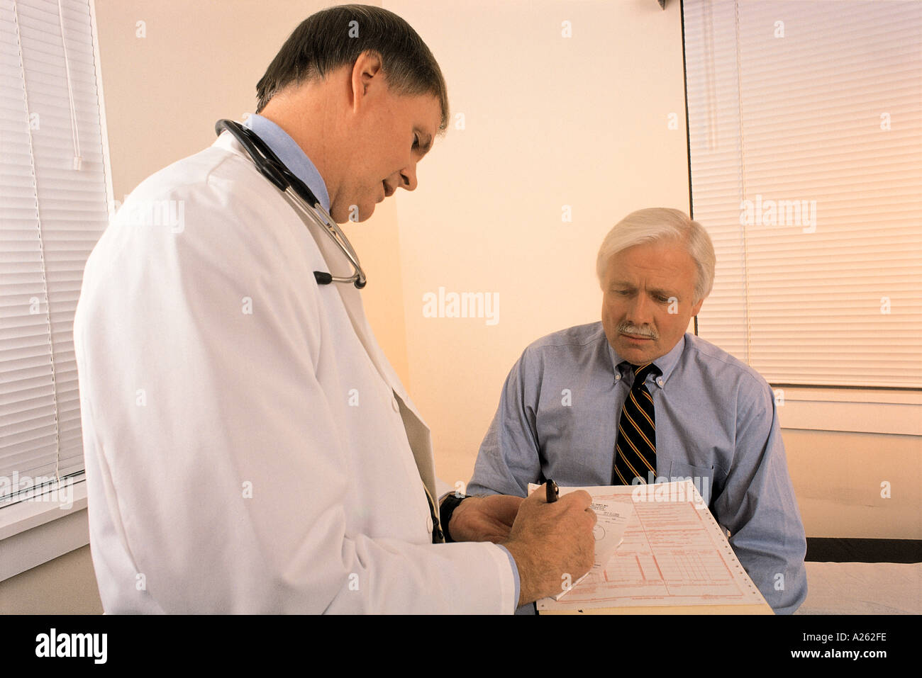 DOCTOR WITH PATIENT TAKING NOTES Stock Photo - Alamy