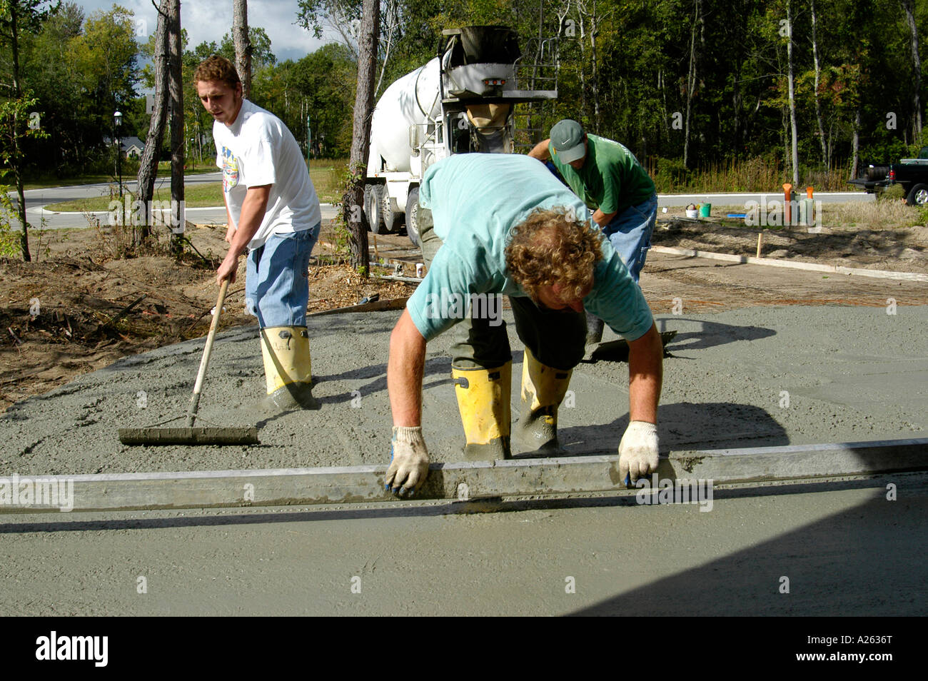 Mason cement workers pour driveway in a new home construction project ...