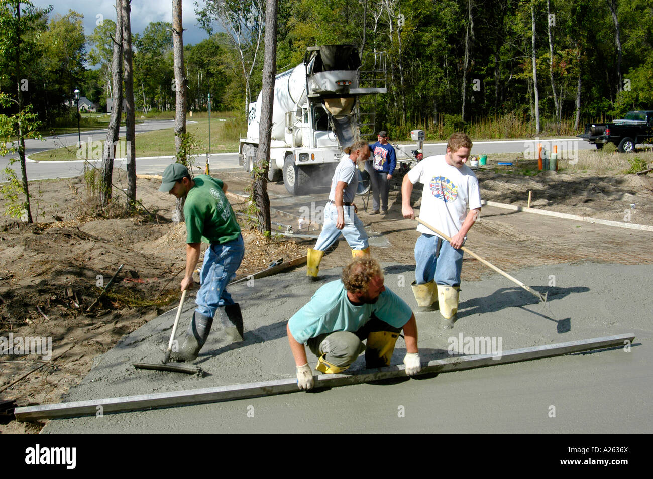 Mason cement workers pour driveway in a new home construction project ...