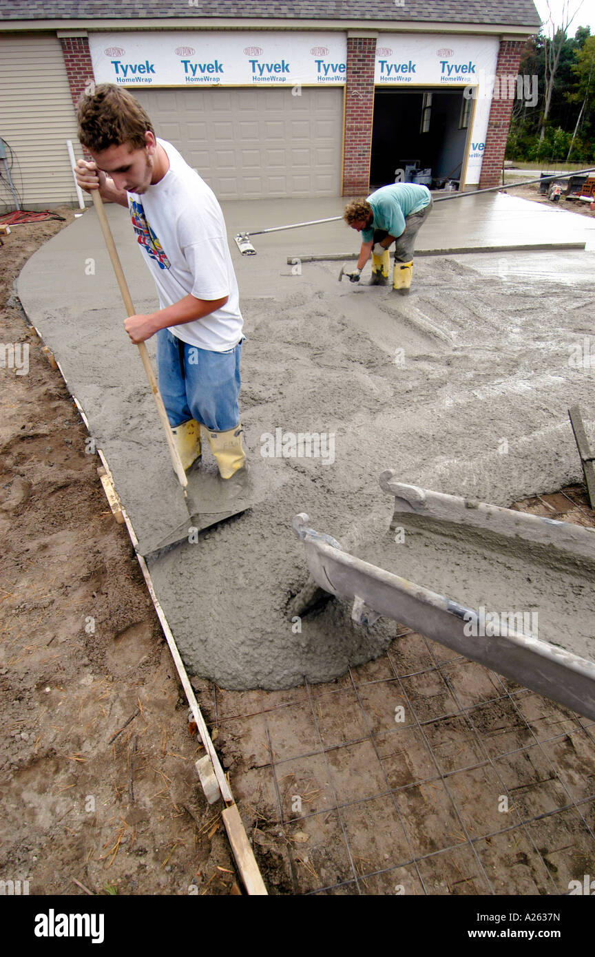 Mason cement workers pour driveway in a new home construction project ...