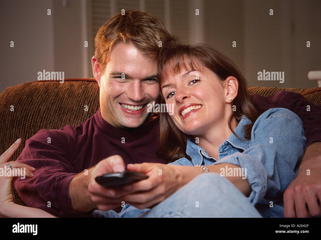 COUPLE SITTING HOLDING REMOTE CONTROL Stock Photo - Alamy